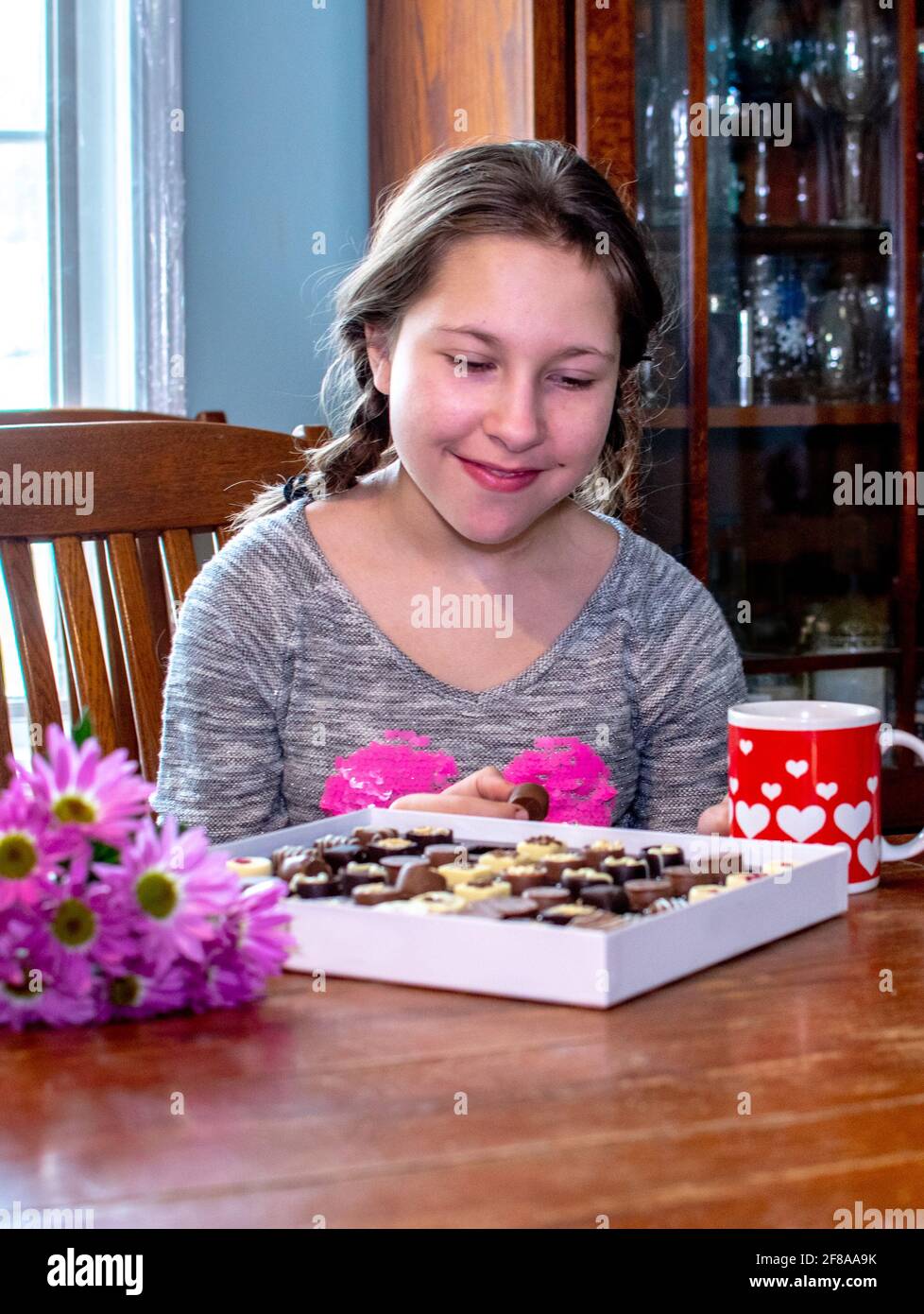 happy girl looks over a box of fancy chocolates trying to decode on her ...