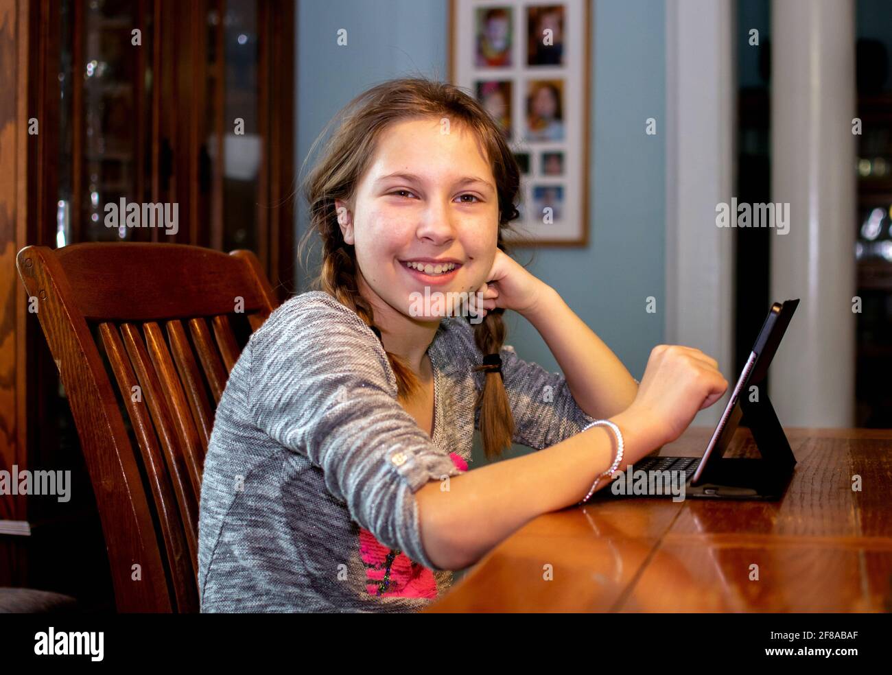 smiling girl poses with her school computer as she works on lessons ...