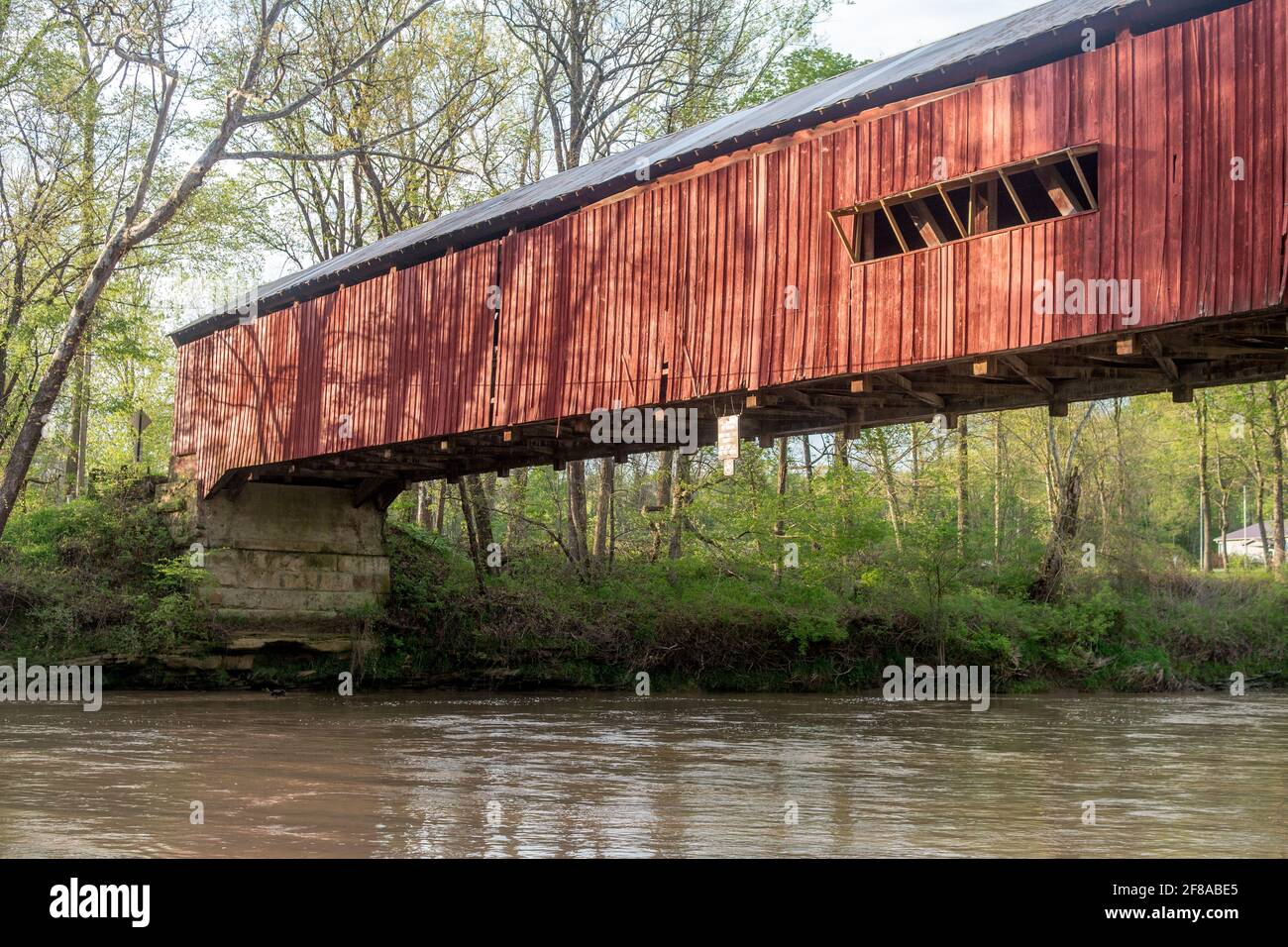 A large, red wooden bridge sits over a river in southern Indiana USA ...
