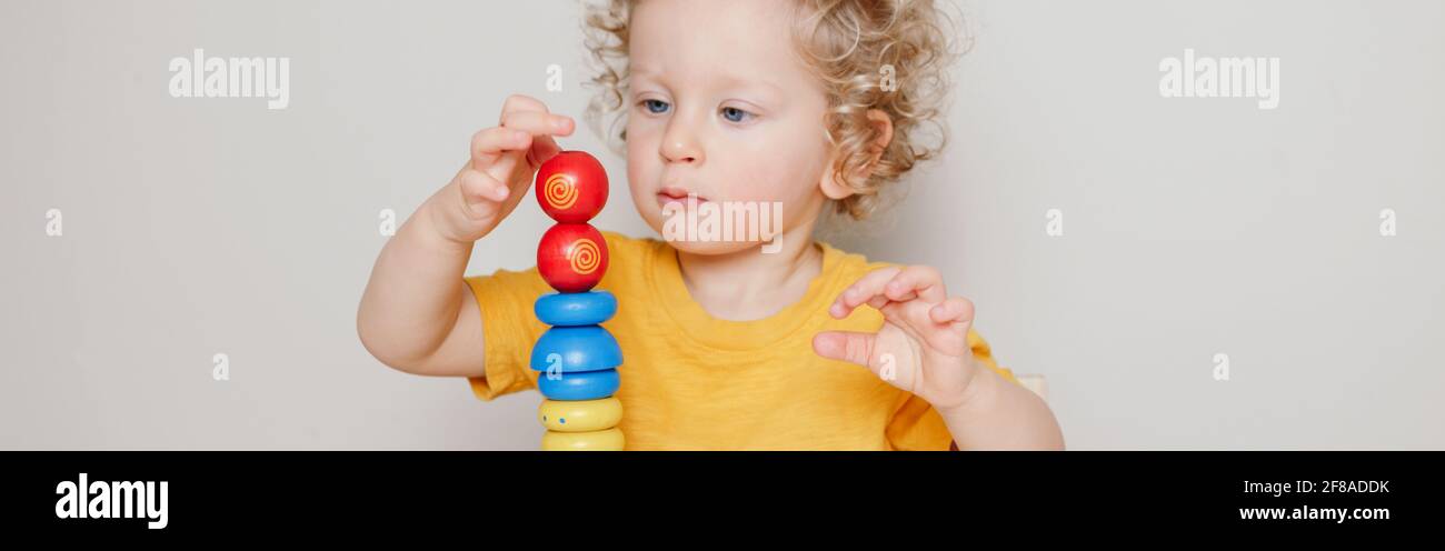 Cute baby toddler playing with learning toy pyramid stacking blocks at ...