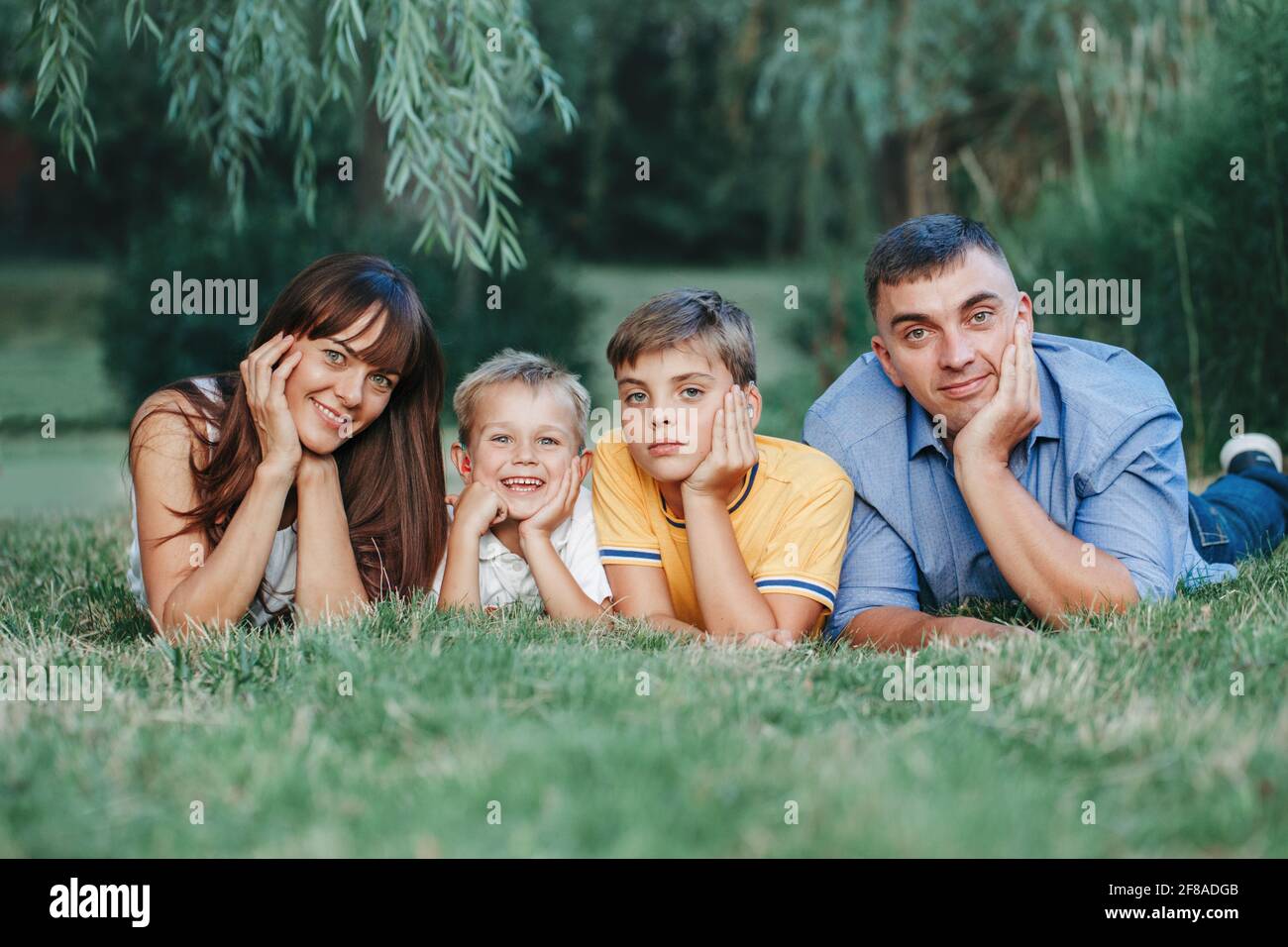 Beautiful happy Caucasian family of four people lying on a ground in ...