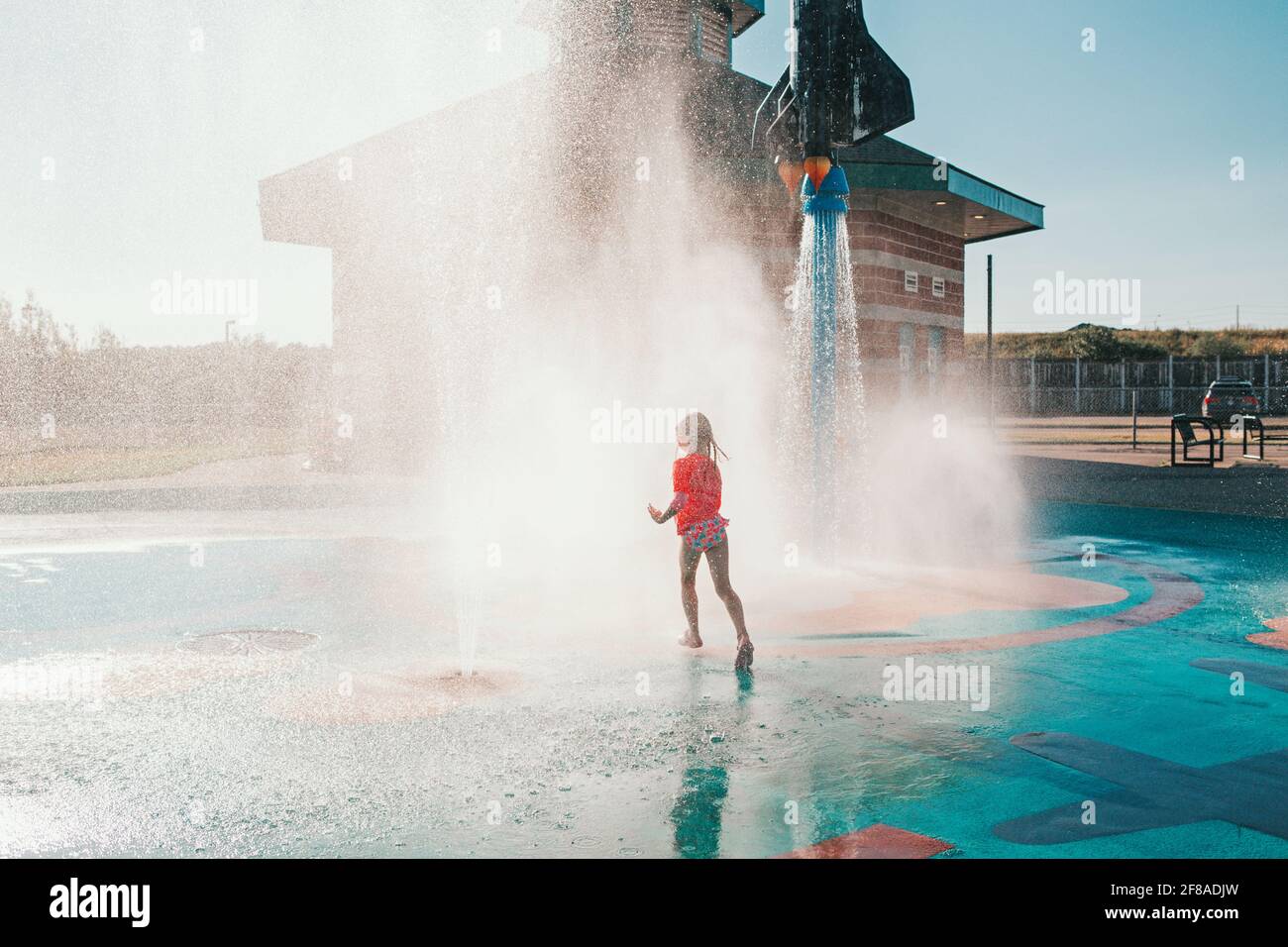 Cute adorable Caucasian funny girl playing on splash pad playground on ...