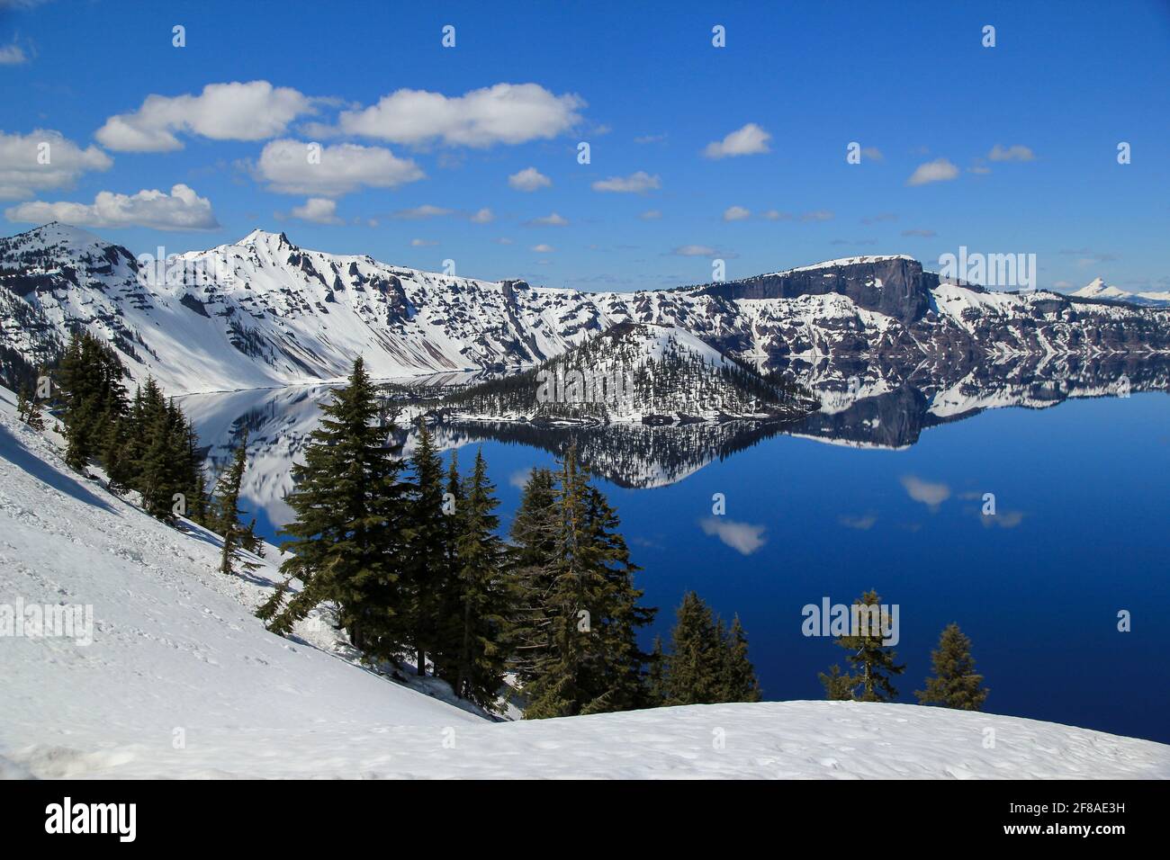 Mountains and blue sky reflected in water of Crater Lake at Crater Lake ...