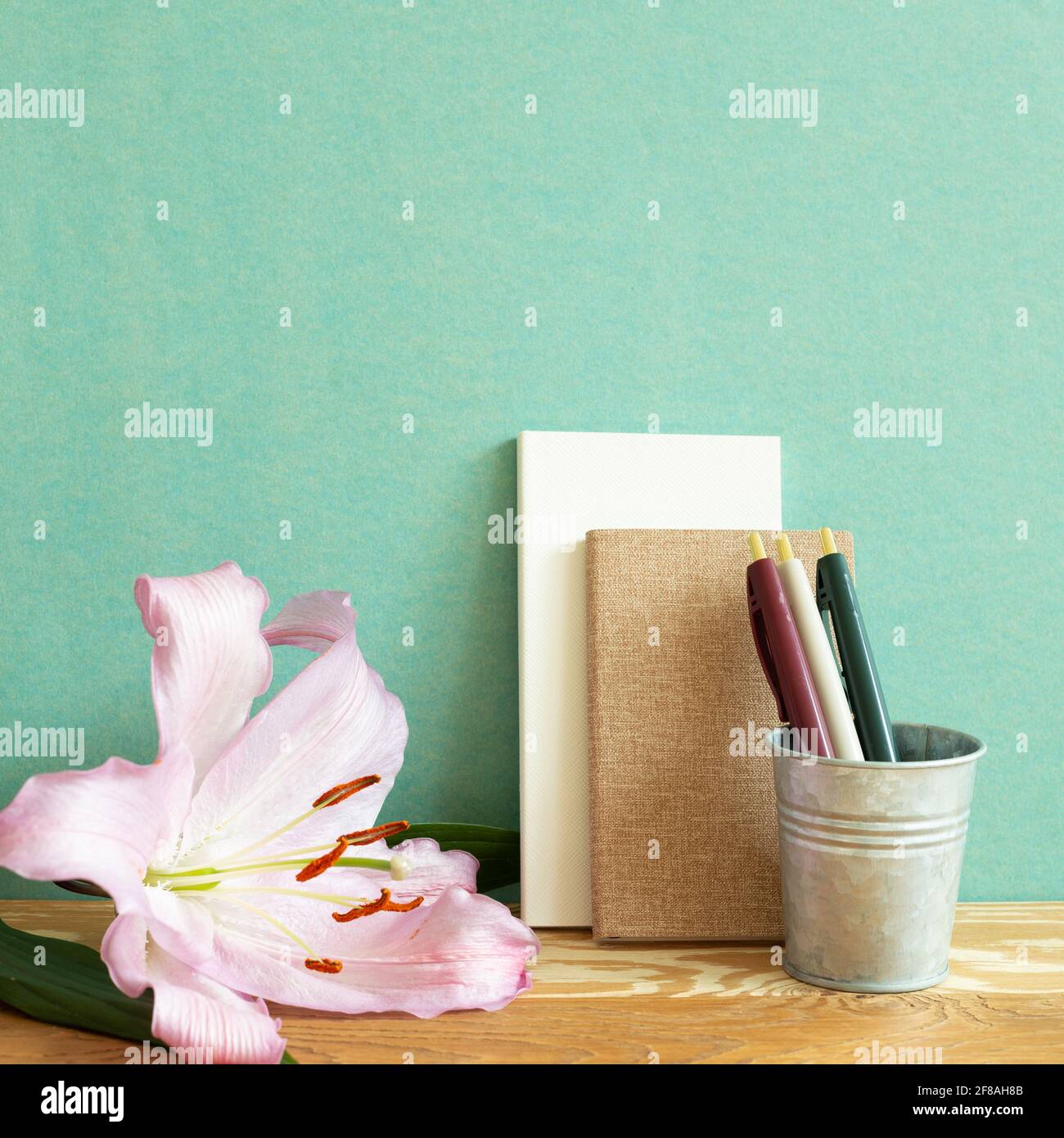 Notebook, pen, flower on wooden desk. green background. Work and study ...