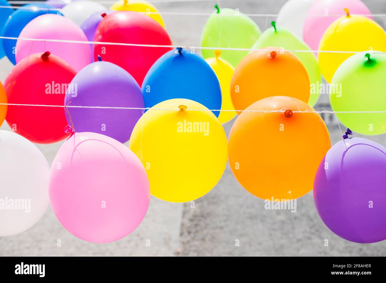 Different colored balloons hanging on the ropes outside Stock Photo - Alamy