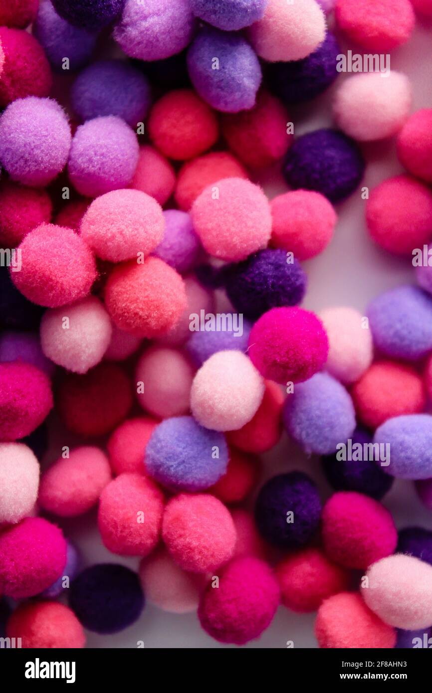 Round pink and purple fluffy balls pompoms on wooden background. Bunch ...
