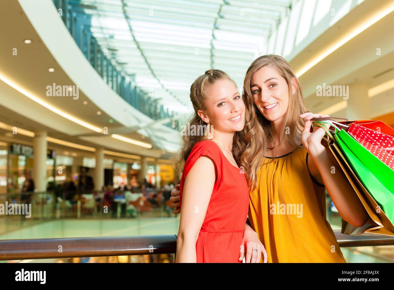 Two female friends with shopping bags having fun while shopping in a ...