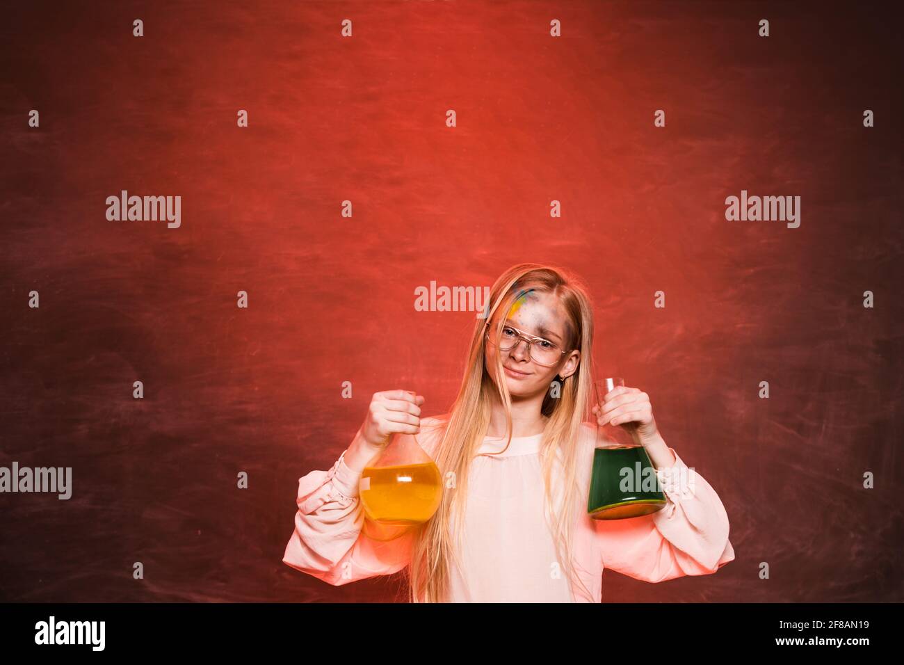 Pretty little girl learning chemistry isolated at red background. Young ...