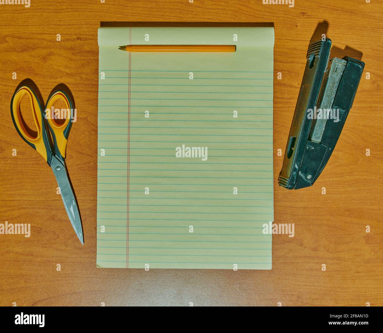 Top view of lined open notebook, scissors, stapler, and pencil on the ...