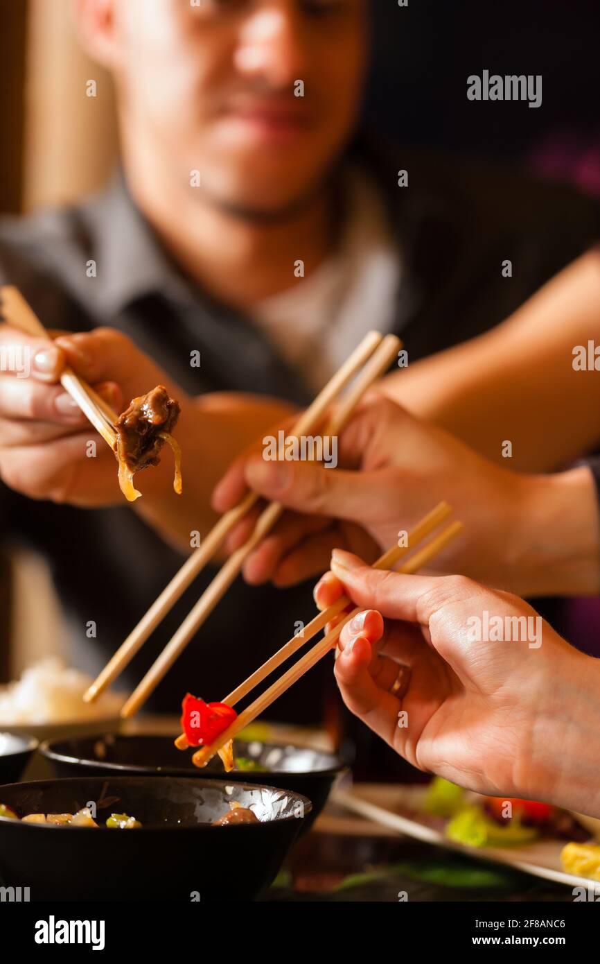 Young people eating in a Thai restaurant, they eating with chopsticks ...