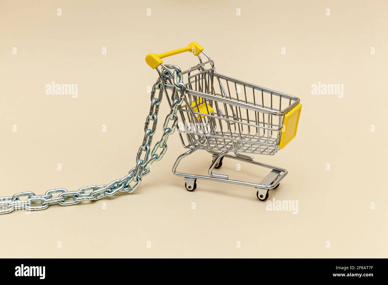 Metal shopping cart with metal chain on a beige background. Concept ...