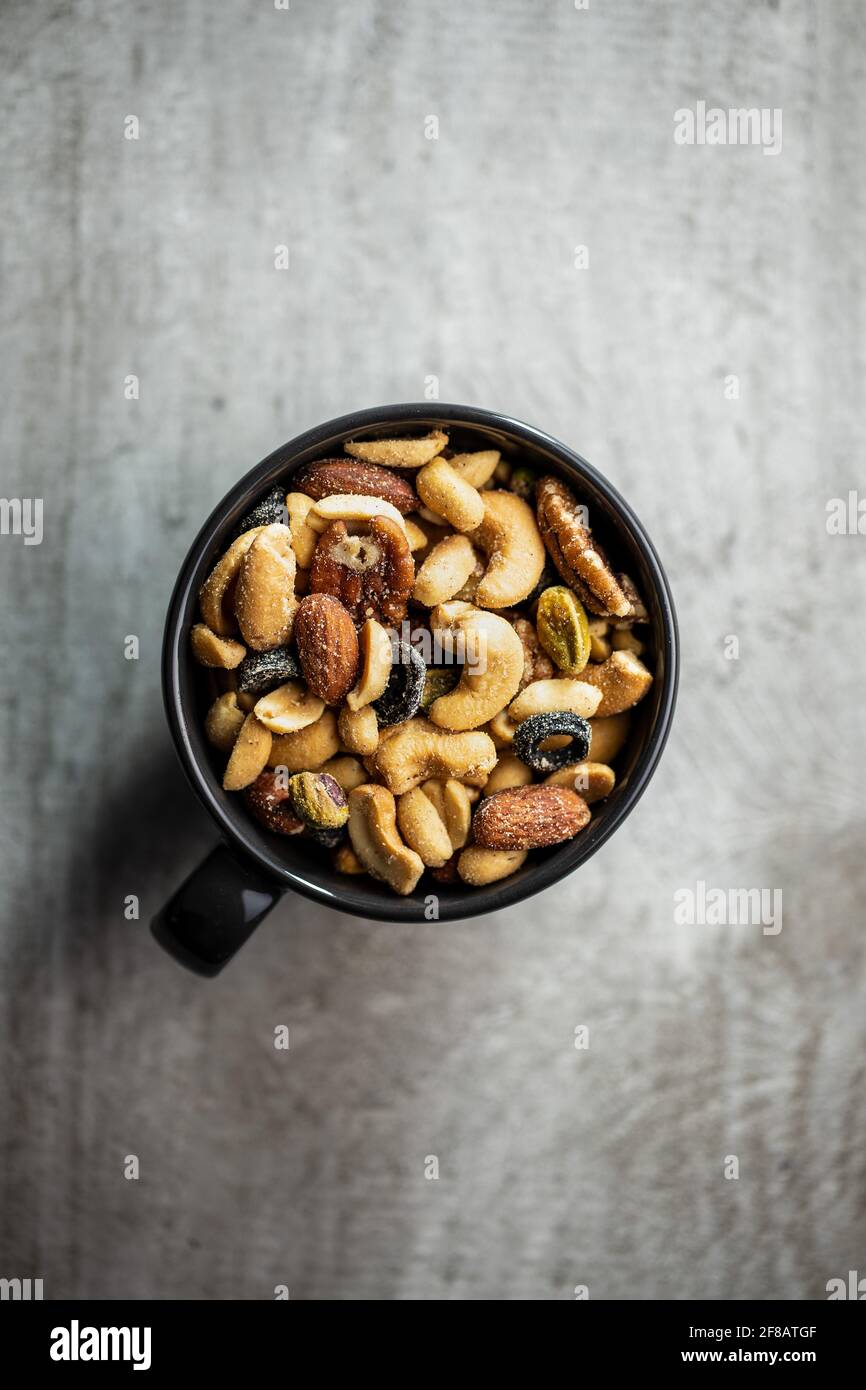 Mix of salted nuts in cup on kitchen table. Top view Stock Photo - Alamy
