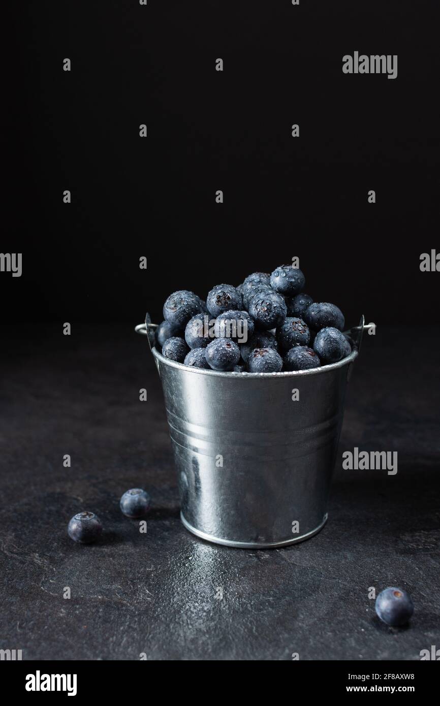 Fresh ripe blueberry in a metal small bucket on black background. Juicy ...
