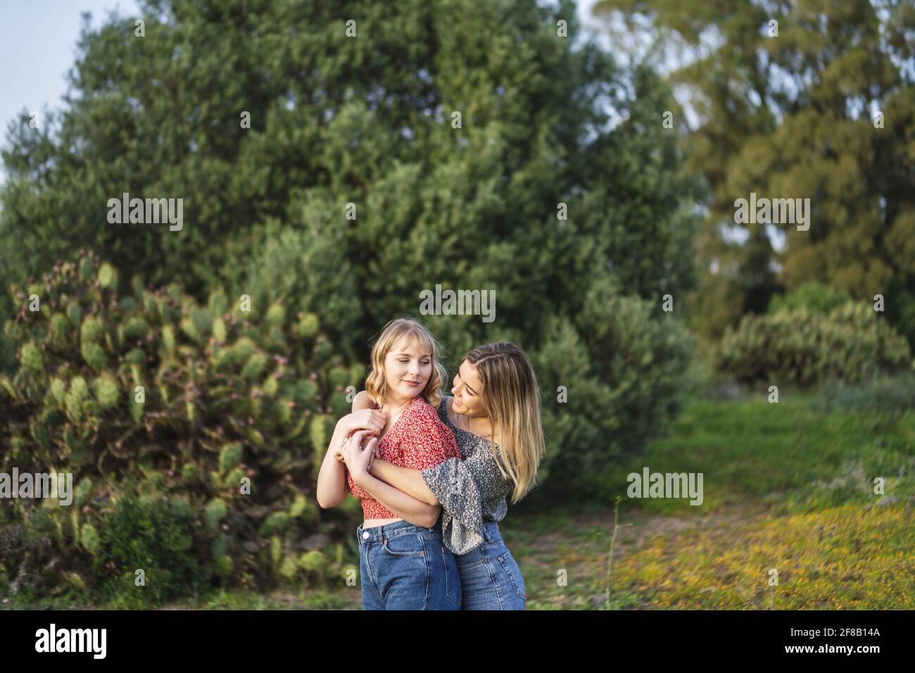 Shallow focus of two young cheerful women hugging in a park in Spain ...