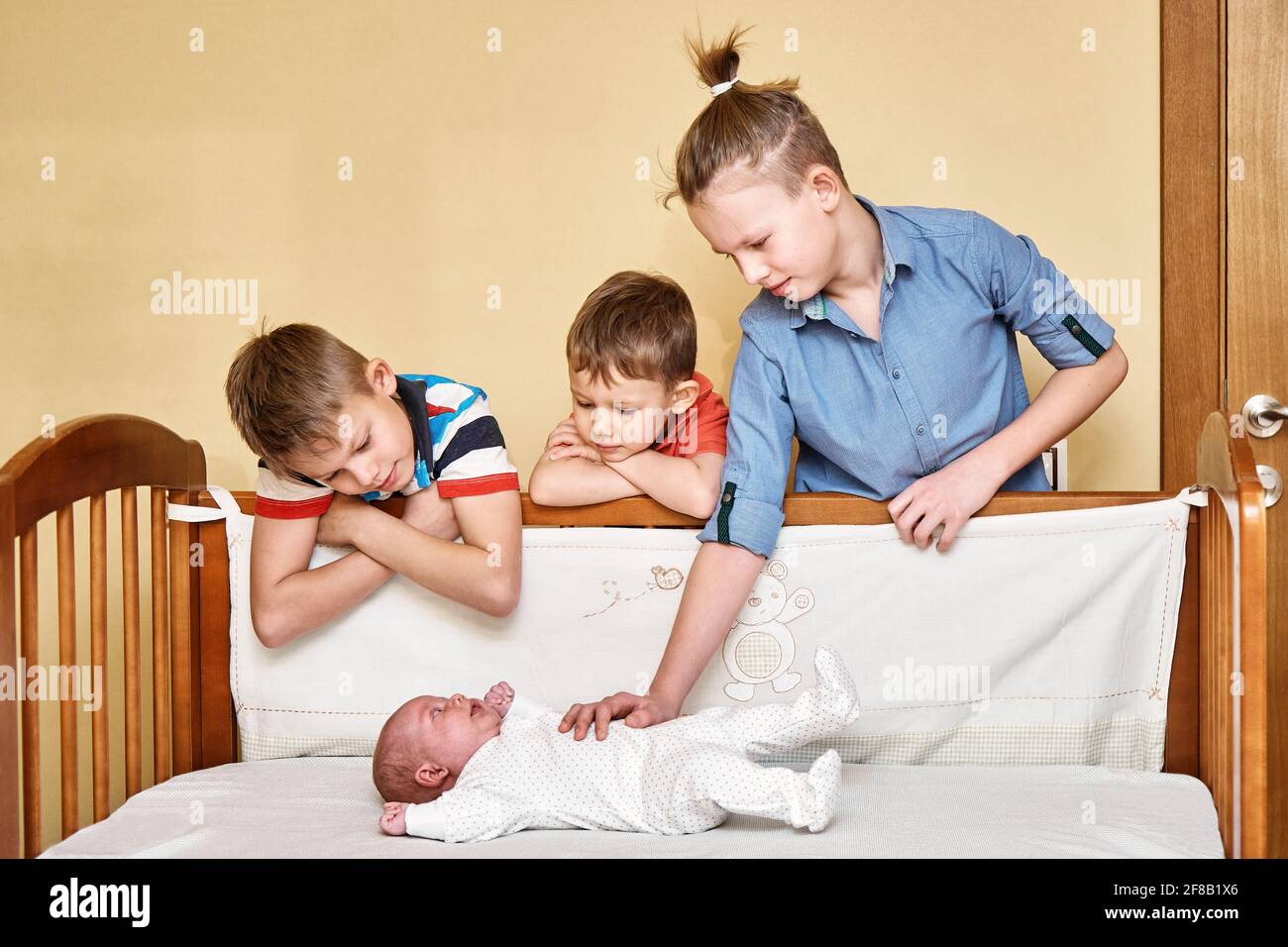 Happy elder brothers look carefully and touch gently lovely baby ...