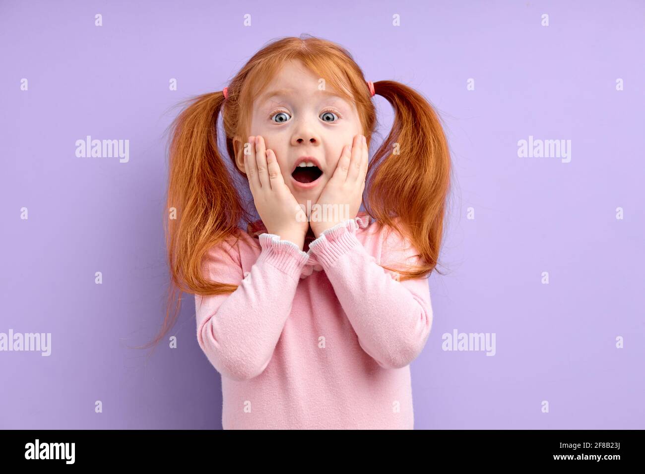 surprised girl with ginger red hair and freckles, stands over purple ...