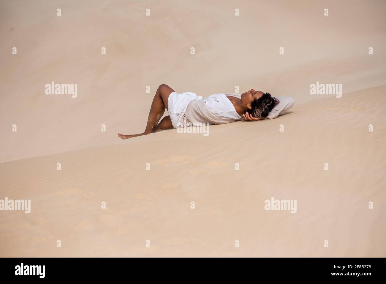 Landscape view of sand dune with woman laying down Stock Photo - Alamy