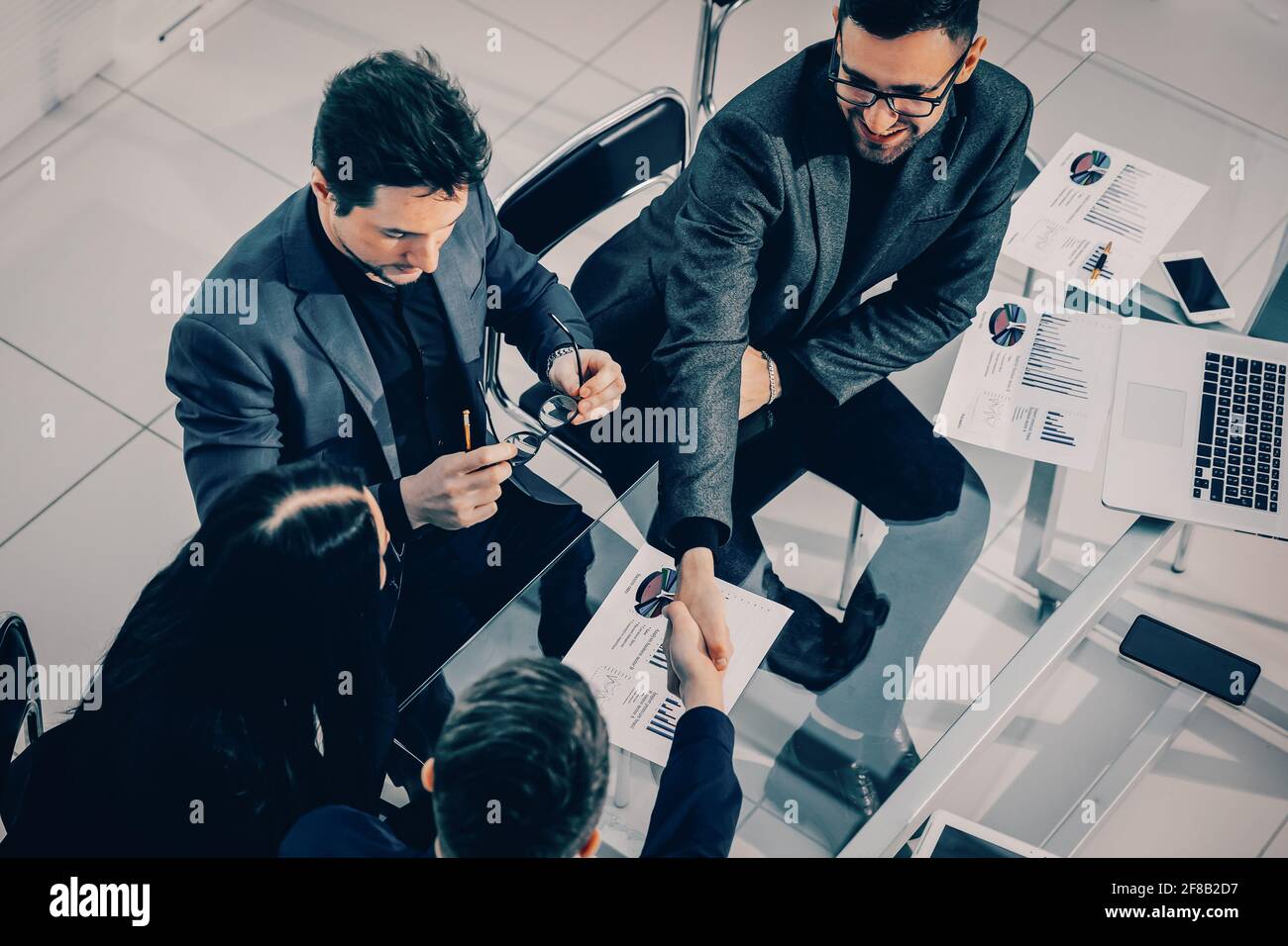 financial partner shake hands over an office Desk Stock Photo - Alamy