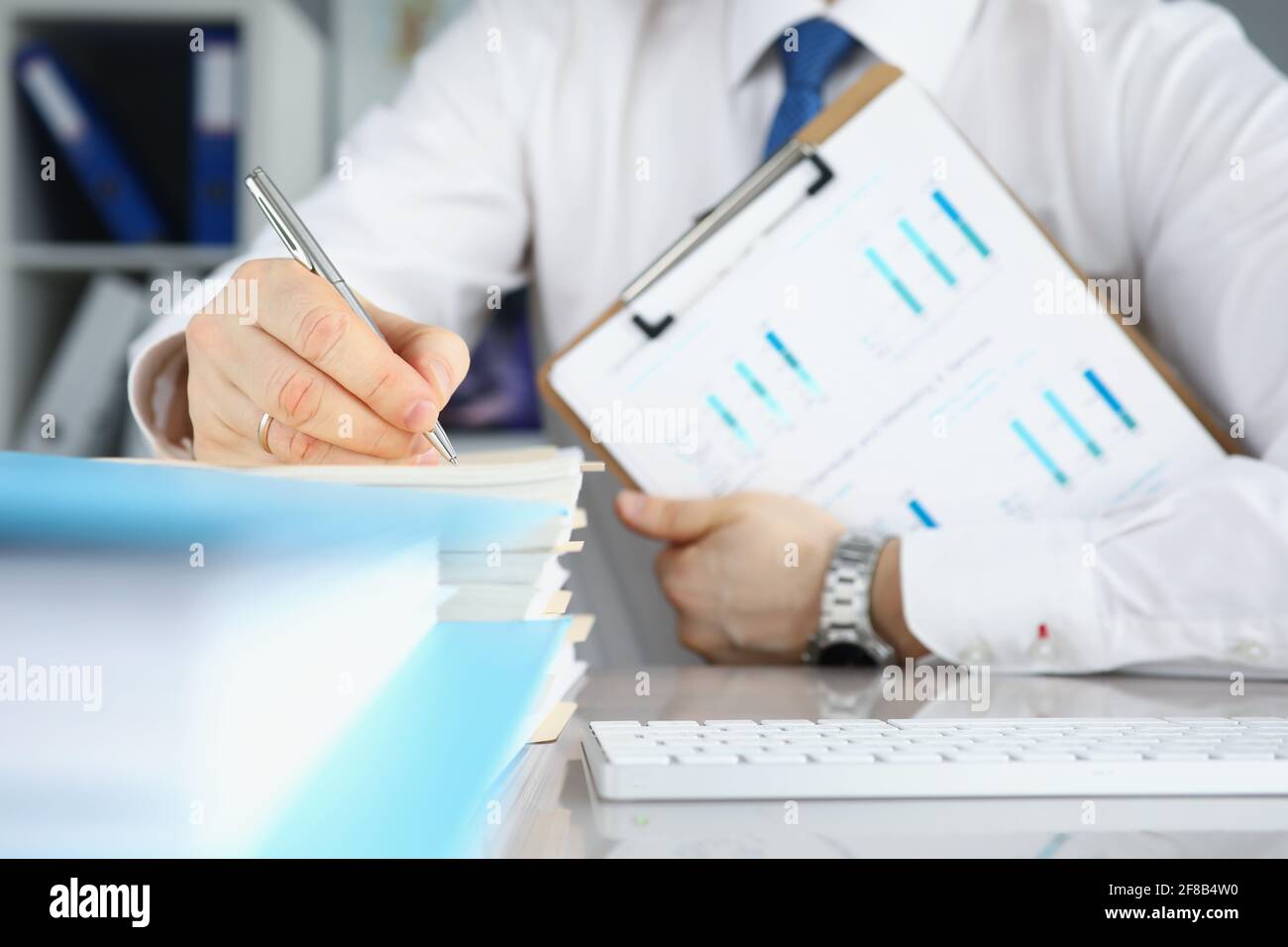 Businessman holds clipboard with commercial charts in his hands and ...