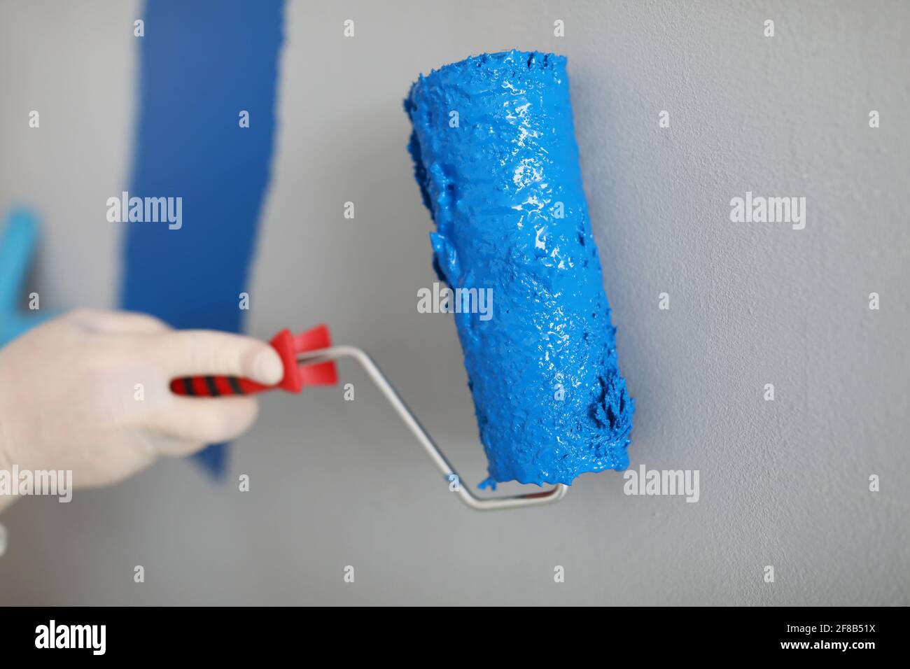 Master paints wall blue with paint roller Stock Photo - Alamy