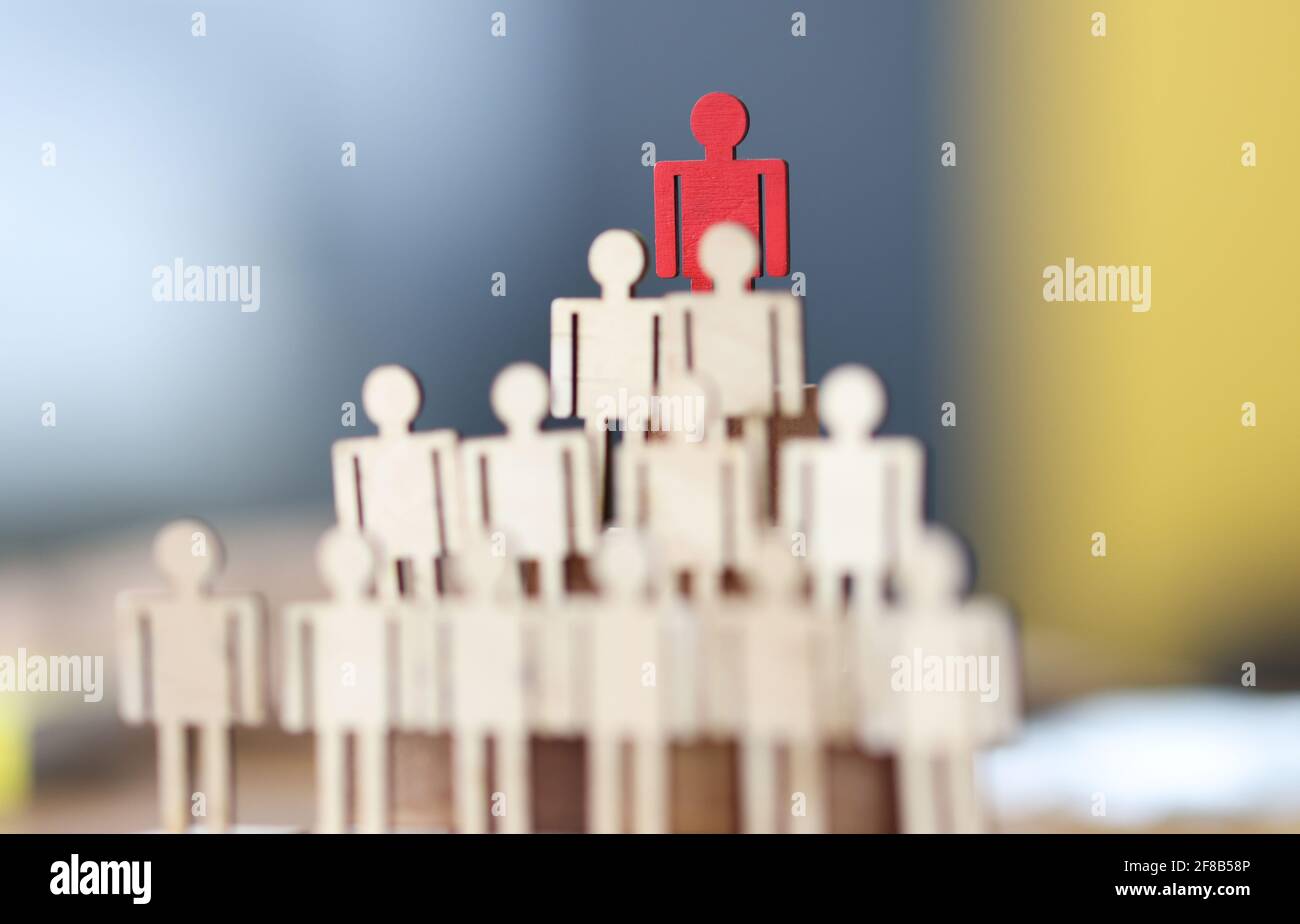 Pyramid of wooden figures of men at very top is only red figure Stock ...