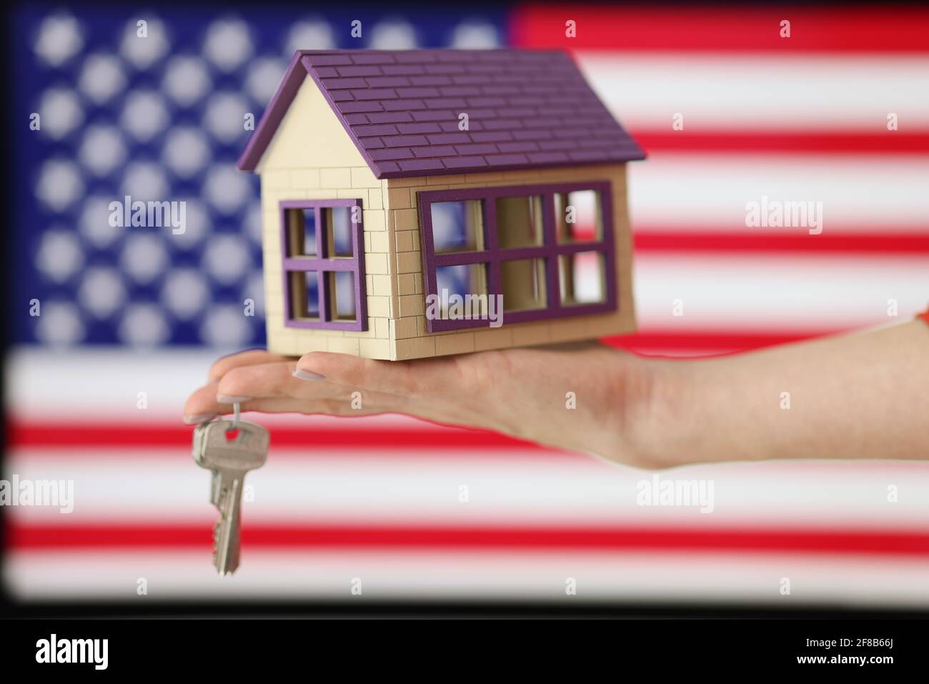 Small house with keys on hand against background of American flag Stock ...