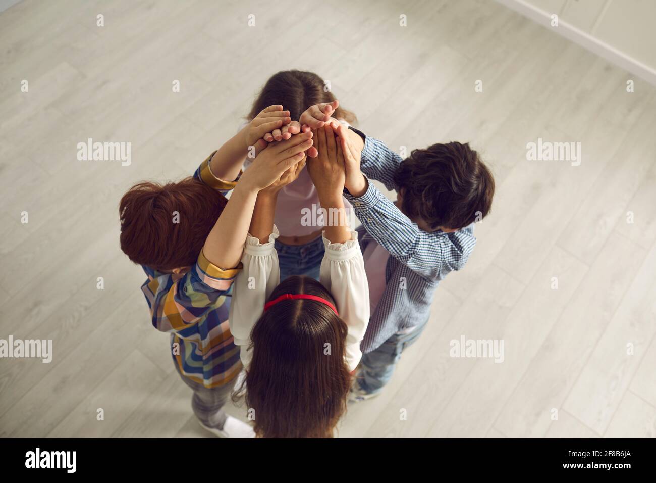 High angle shot of team of little children standing close in circle and ...