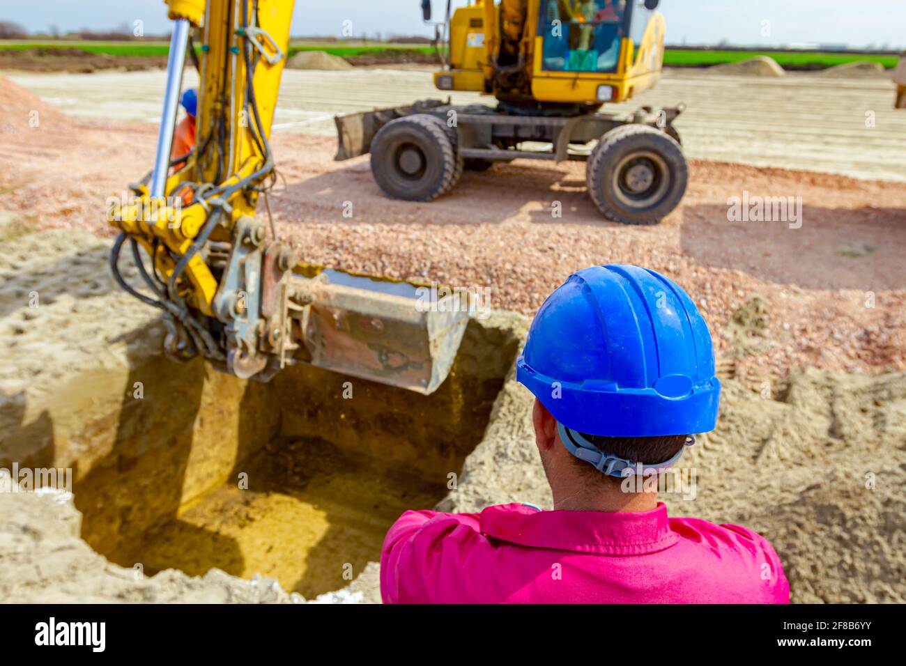 View from behind on construction worker, foreman, with safety blue ...
