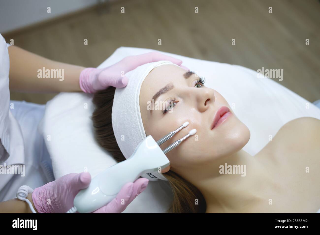 Cosmetologist does microcurrent procedure of a beautiful woman. Women's cosmetology in the ...