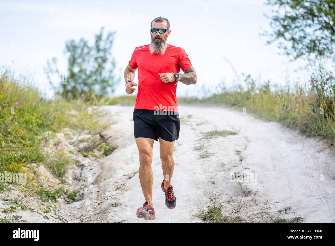 Sporty bearded man running on the path at hillside Stock Photo - Alamy