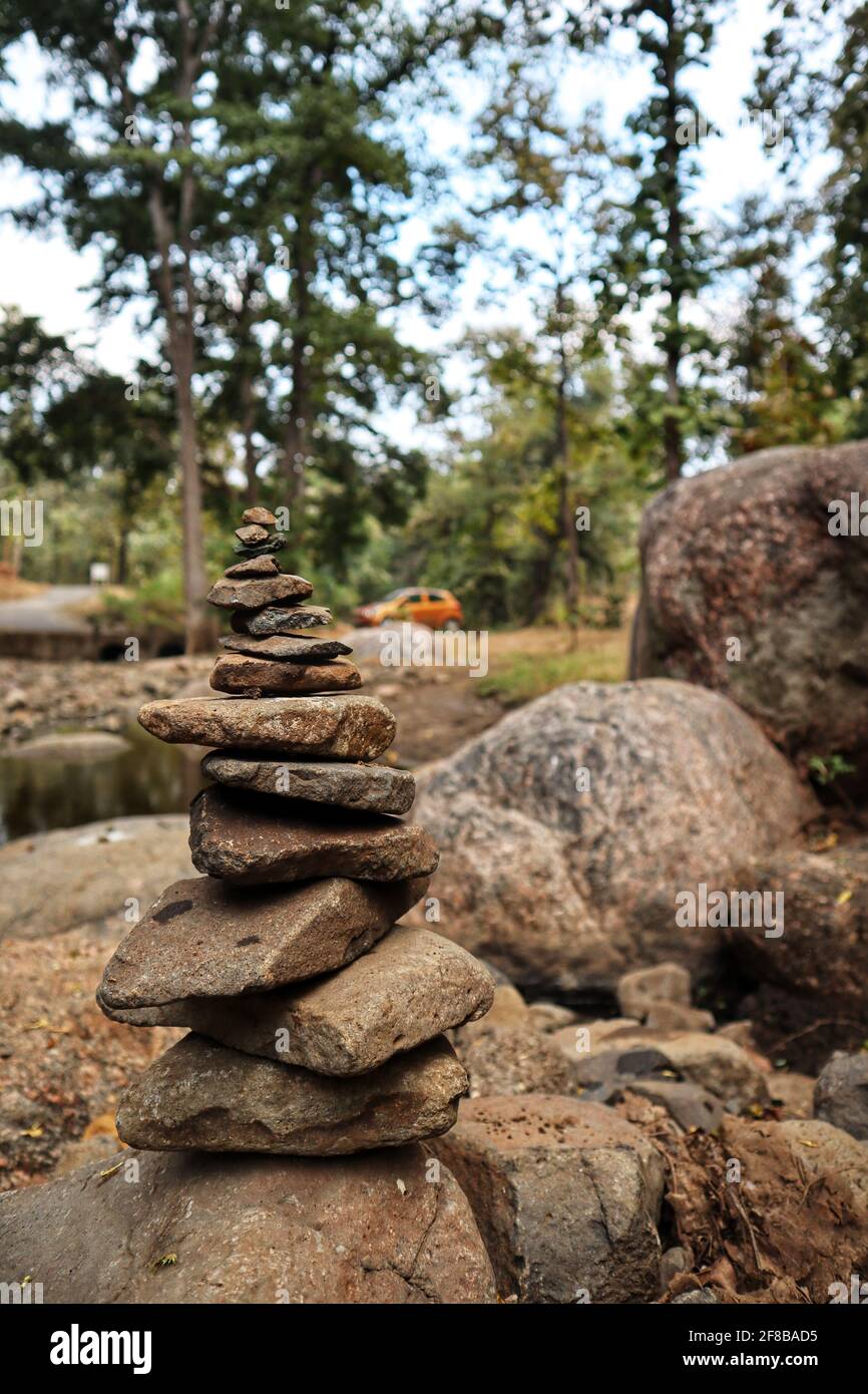 Vertical shot of a small pyramid piled from stones on the pine trees ...