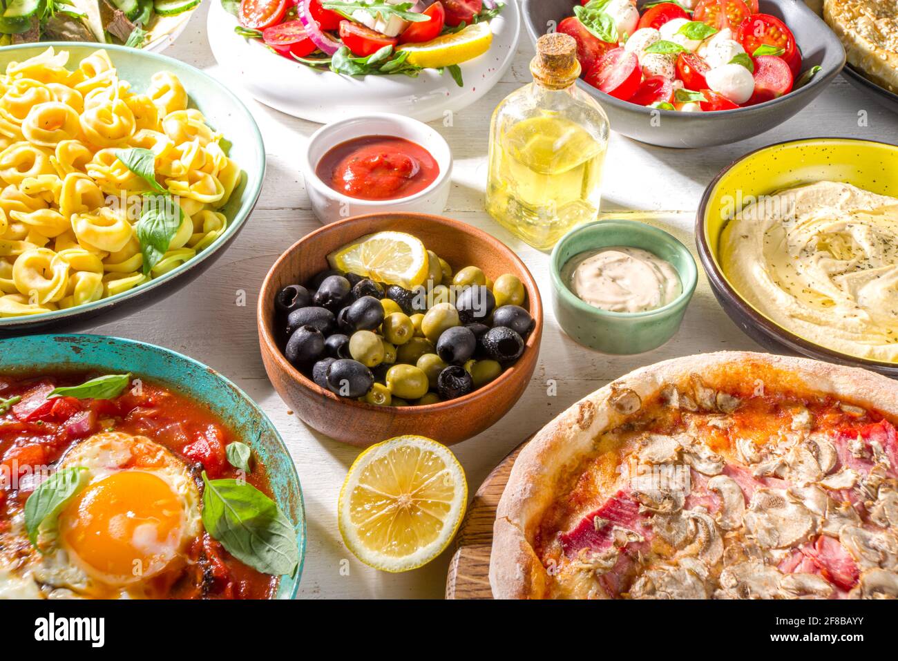 Set of different Mediterranean foods: olives, mozzarella tomato salad ...
