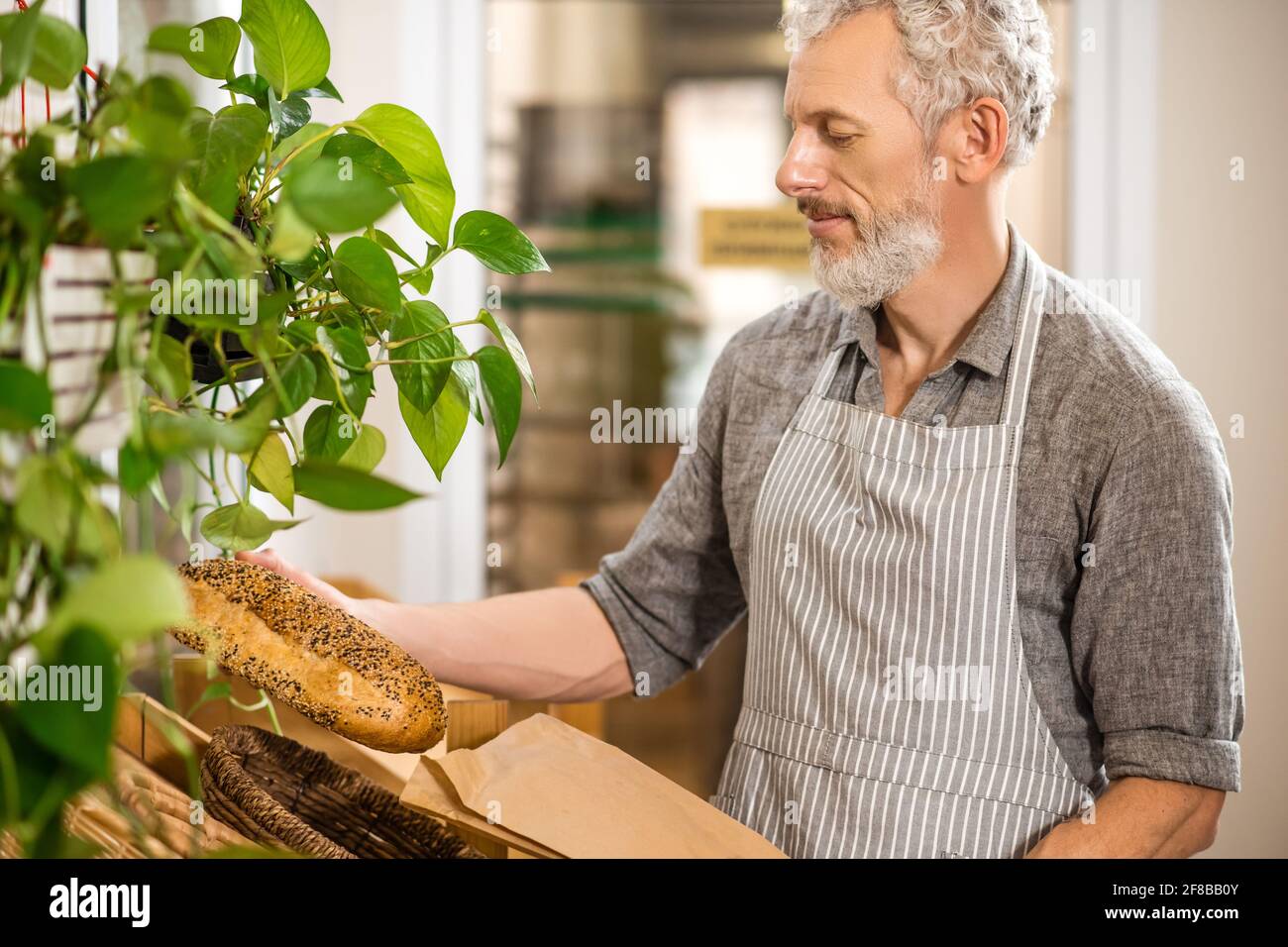 Profile of serious man in apron near bread rack Stock Photo - Alamy