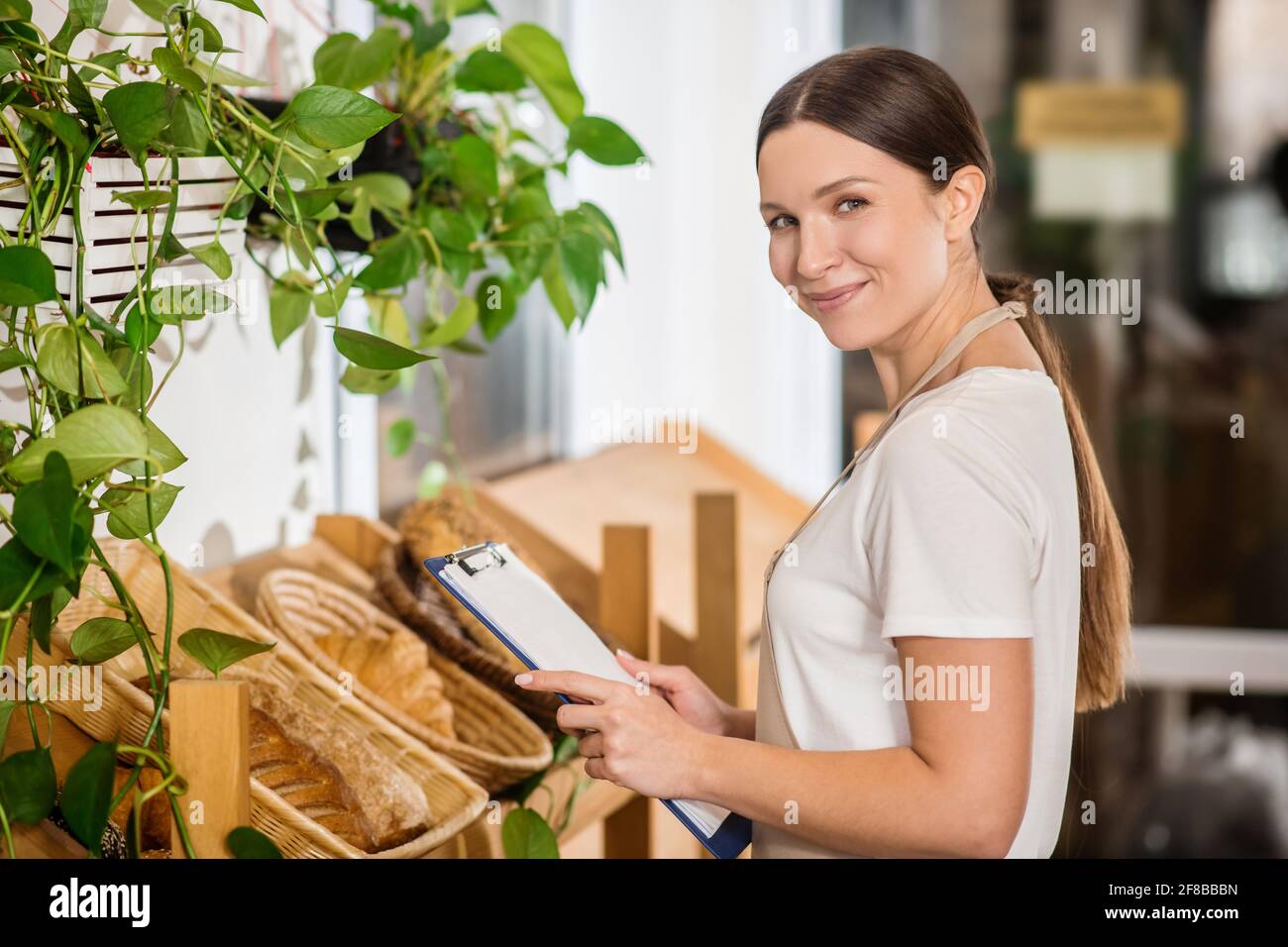 Woman with folder near rack of bakery products Stock Photo - Alamy