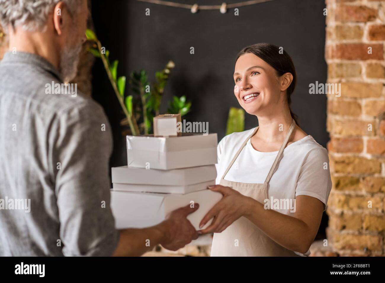 Woman and man passing packing boxes to each other Stock Photo - Alamy