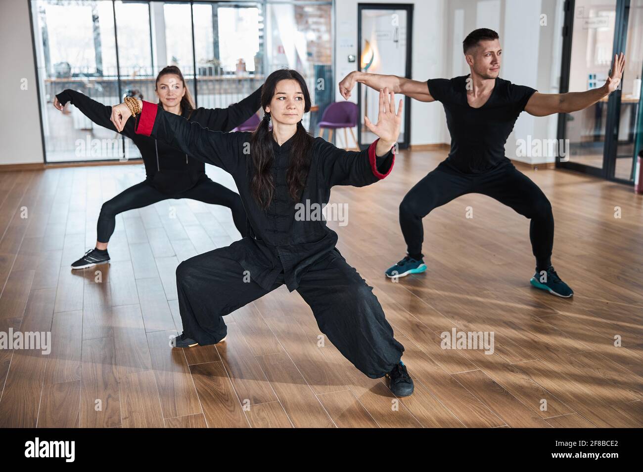 Woman coach teaching single whip pose to students Stock Photo - Alamy