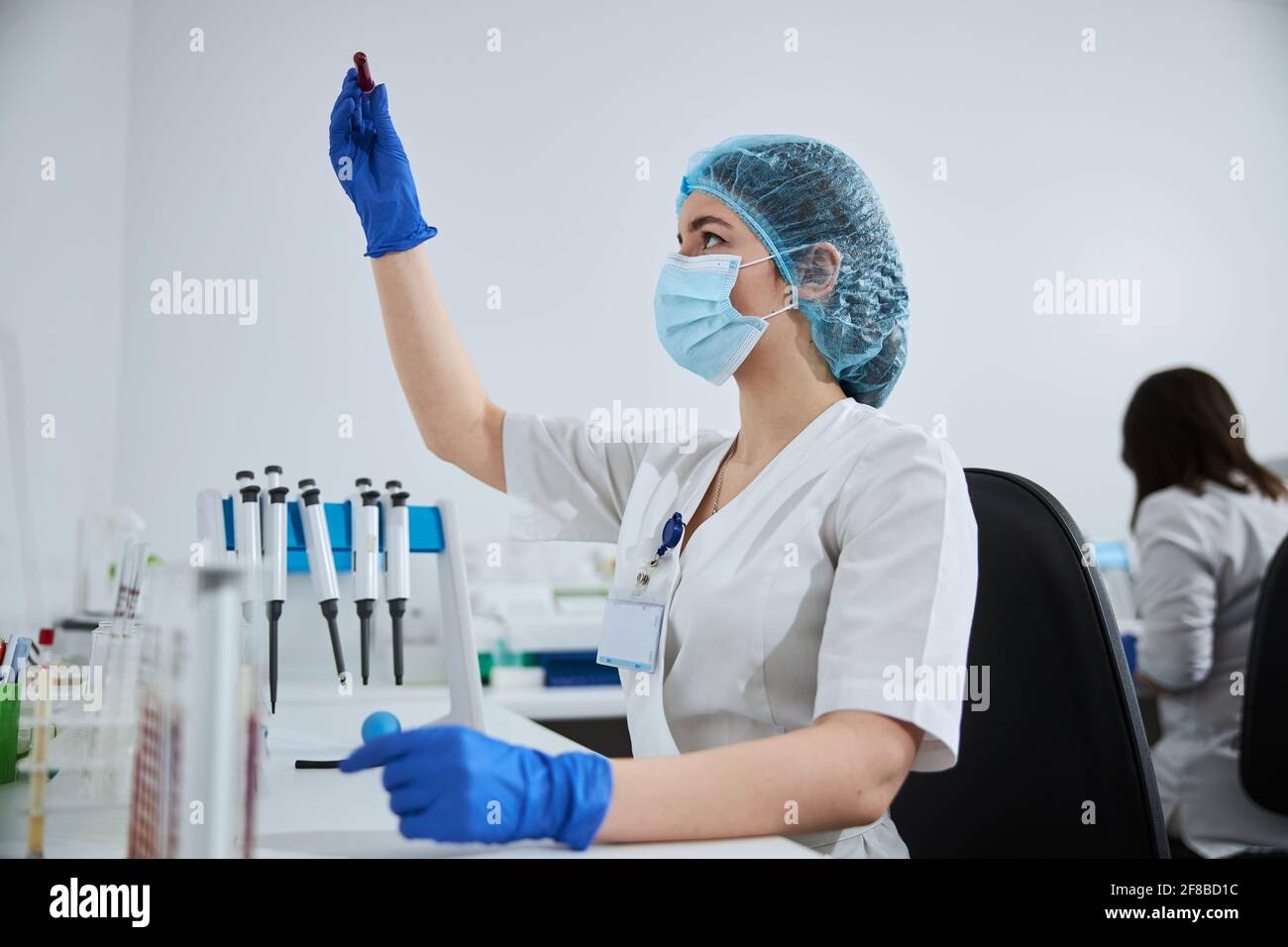 Lab technician in sterile latex gloves holding a vacutainer tube Stock ...