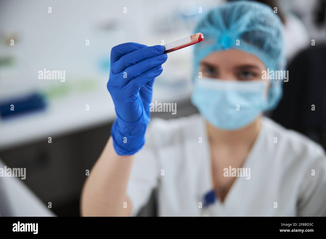 Female biochemist examining a clinical specimen in a test tube Stock ...