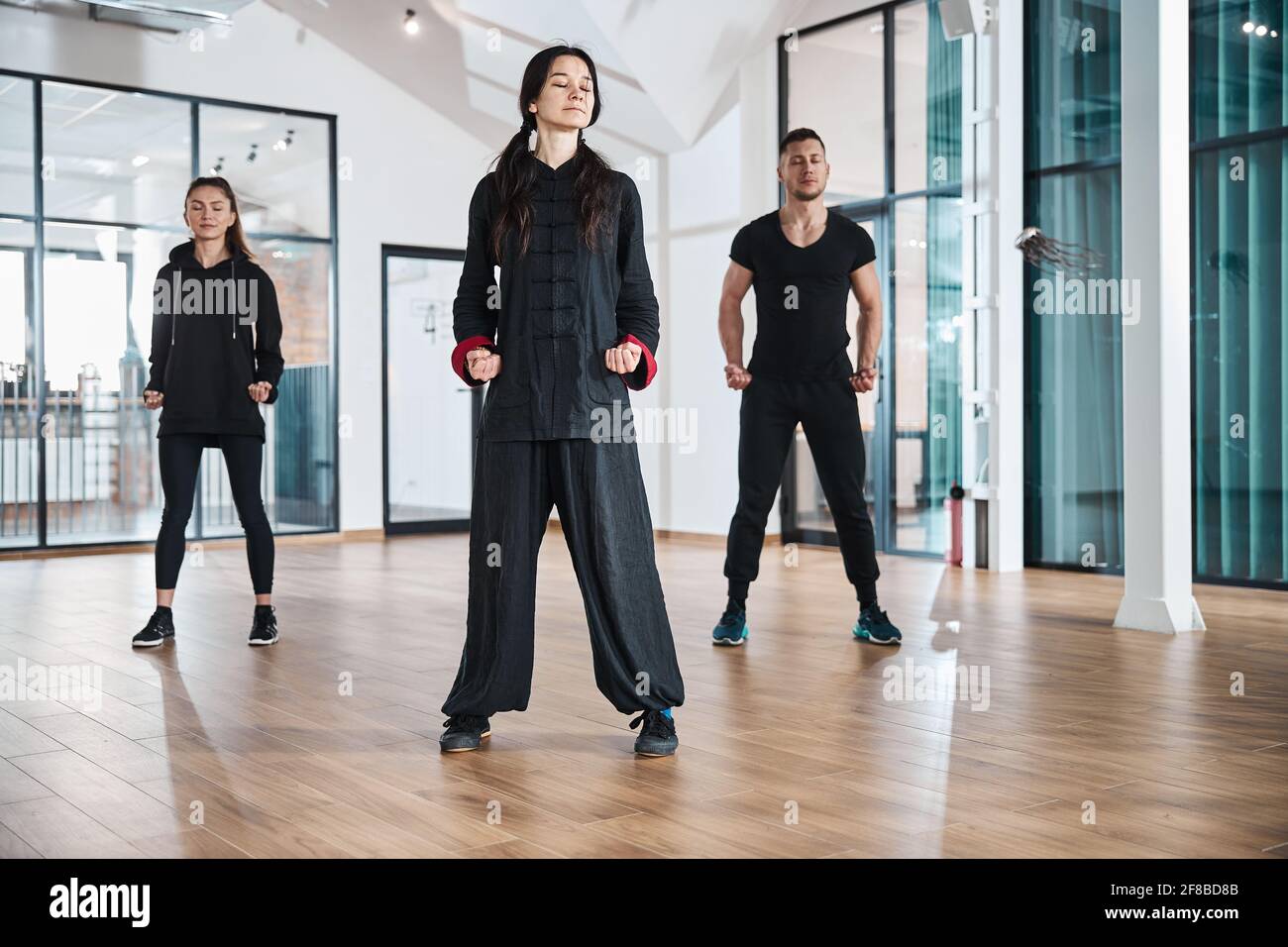 Trainer with students meditating in standing position Stock Photo - Alamy
