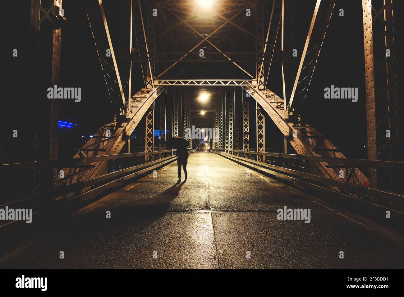 A man with an umbrella walks across the bridge at night Stock Photo - Alamy