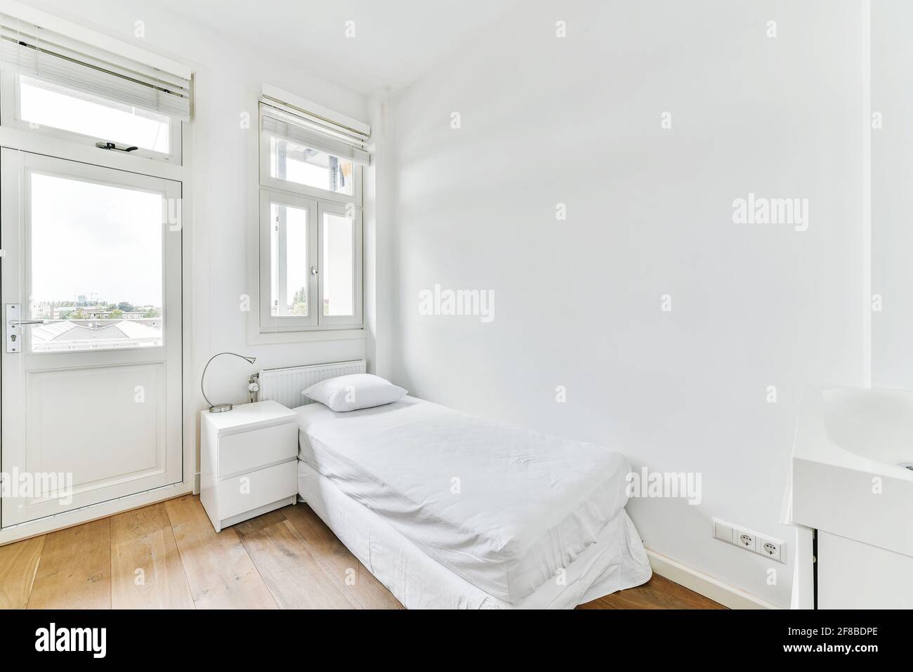 Bed and bedside table near window Stock Photo - Alamy