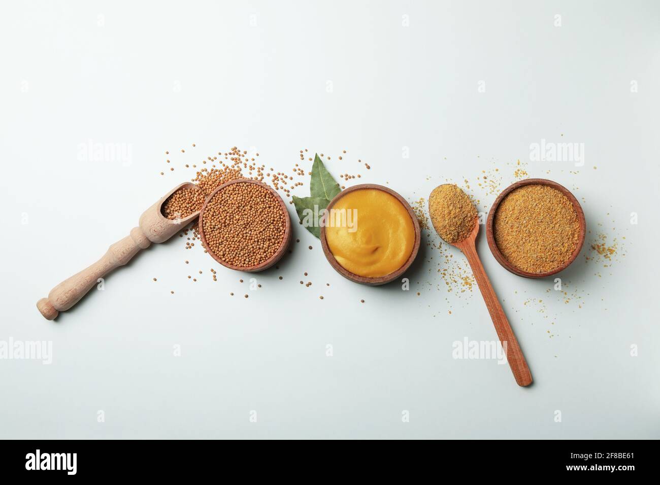 Bowls with mustard seeds, sauce and powder on white background Stock ...