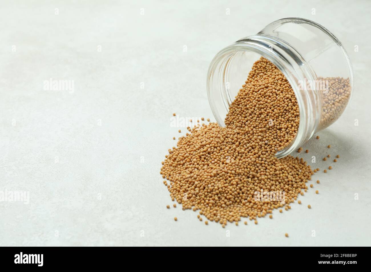 Glass jar with mustard seeds on white textured background Stock Photo ...