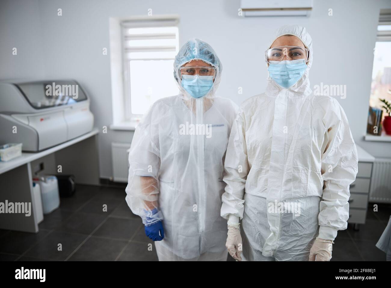 Two serious scientists in hazmat suits standing in the research lab ...