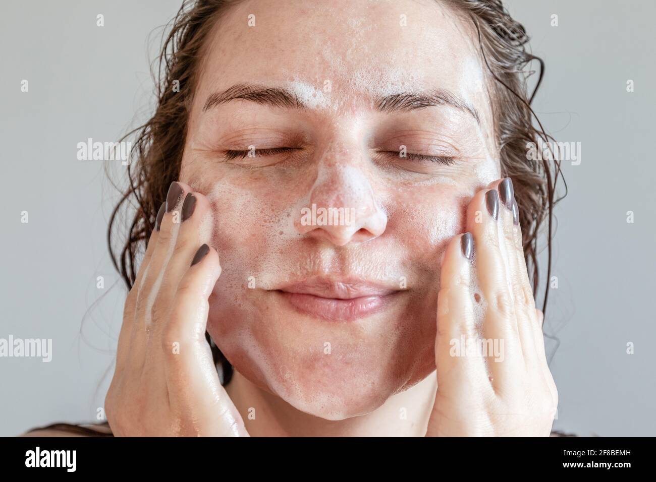 Close up happy woman smile and washing face by make bubble facial foam ...