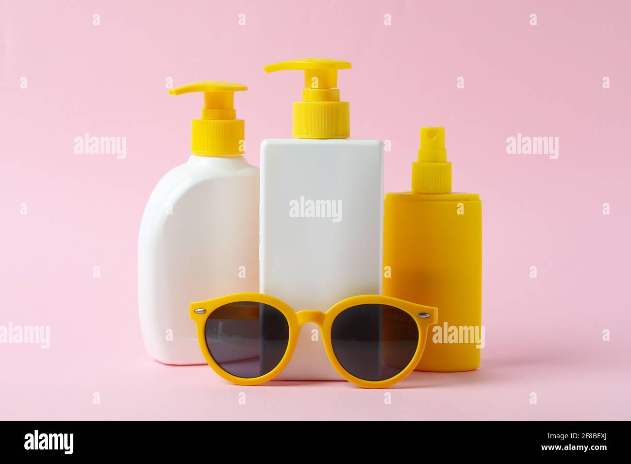 Sunscreen bottles and sunglasses on pink background Stock Photo - Alamy