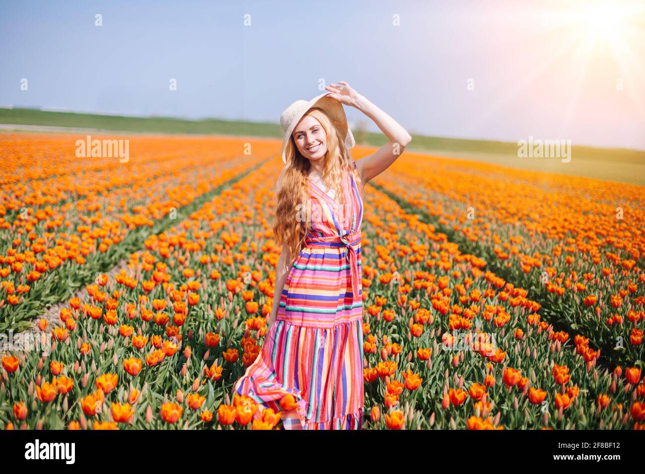 Beautiful red hair woman wearing in striped dress standing on colorful ...