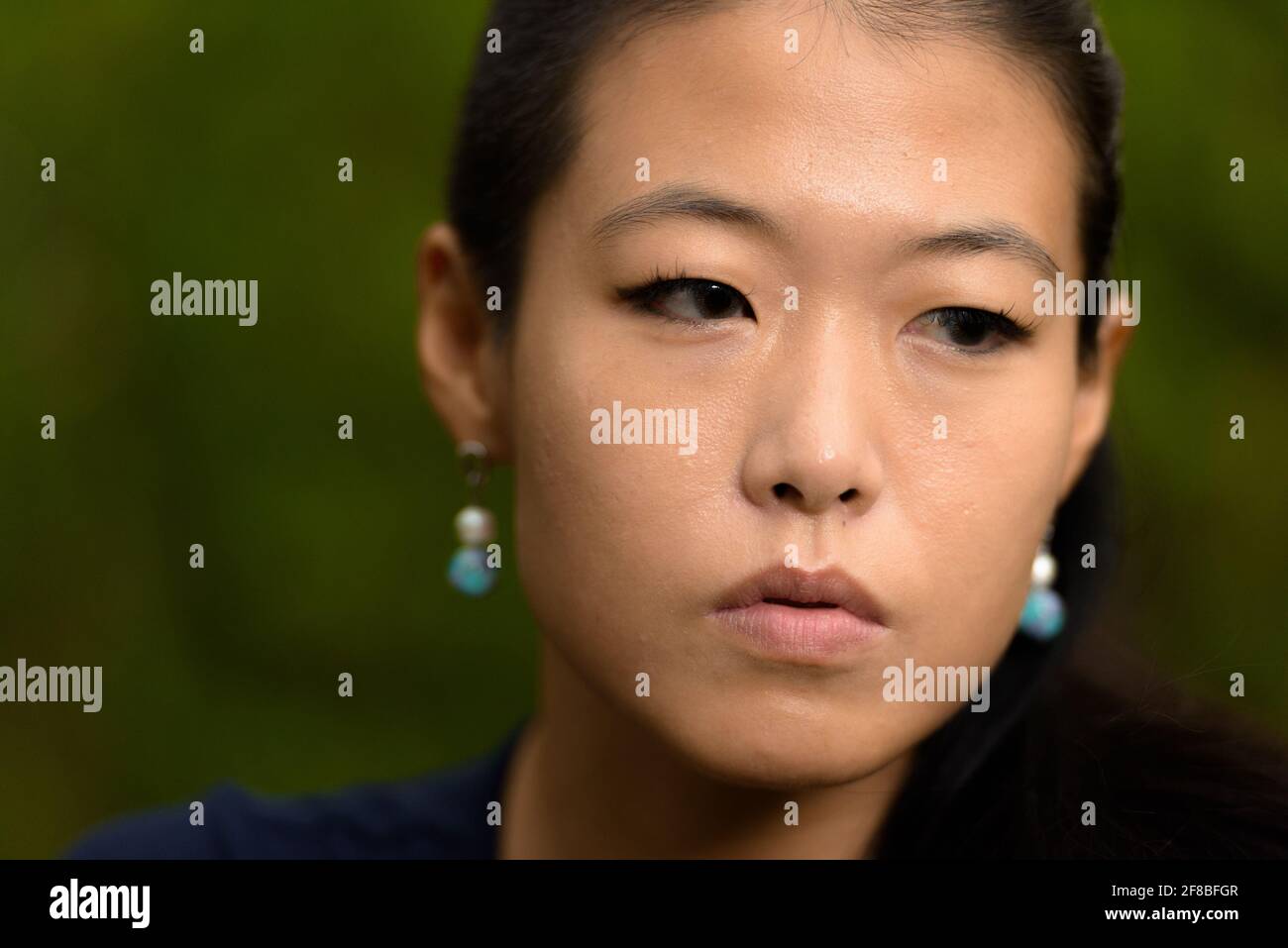Close-up portrait of beautiful rebel Asian woman face looking serious ...