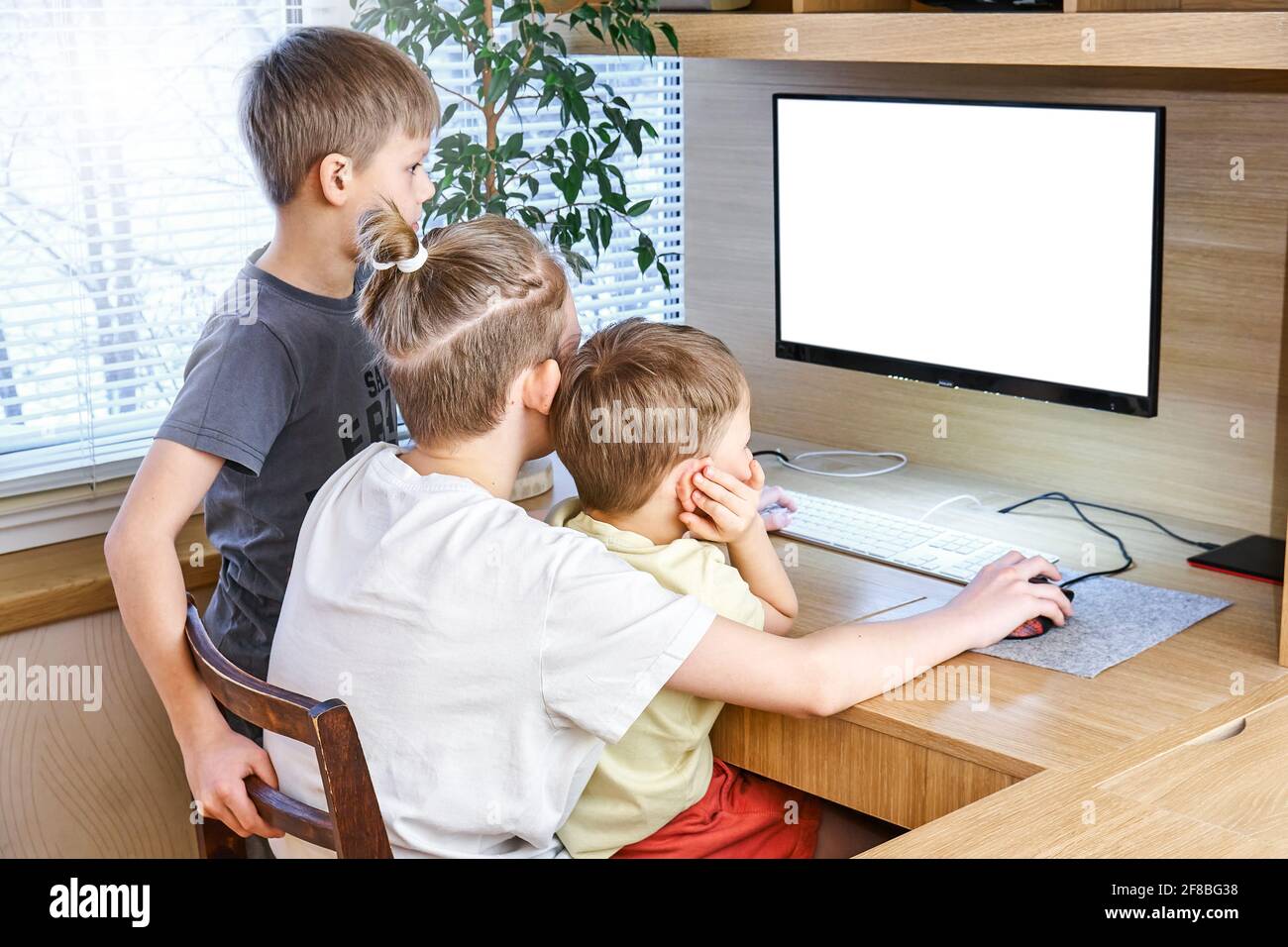 Young boy pupils sit on chair at wooden computer desk looking into ...