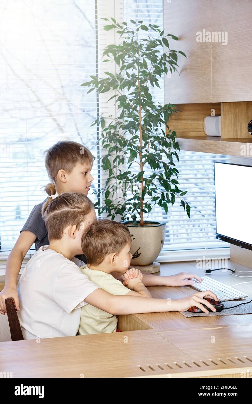 Young boy pupils sit on chair at wooden computer desk looking into ...
